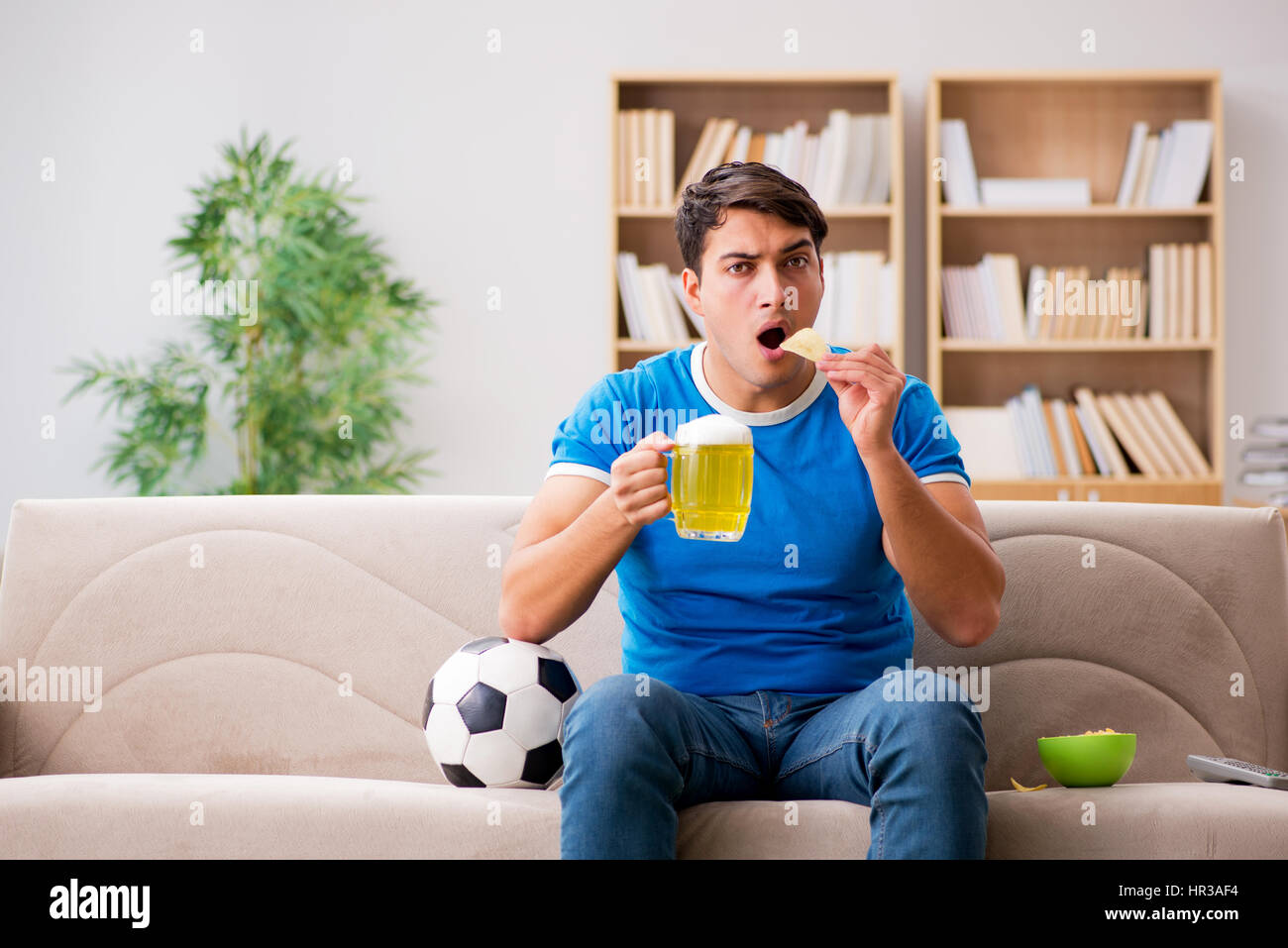Man watching football at home sitting in couch Stock Photo - Alamy