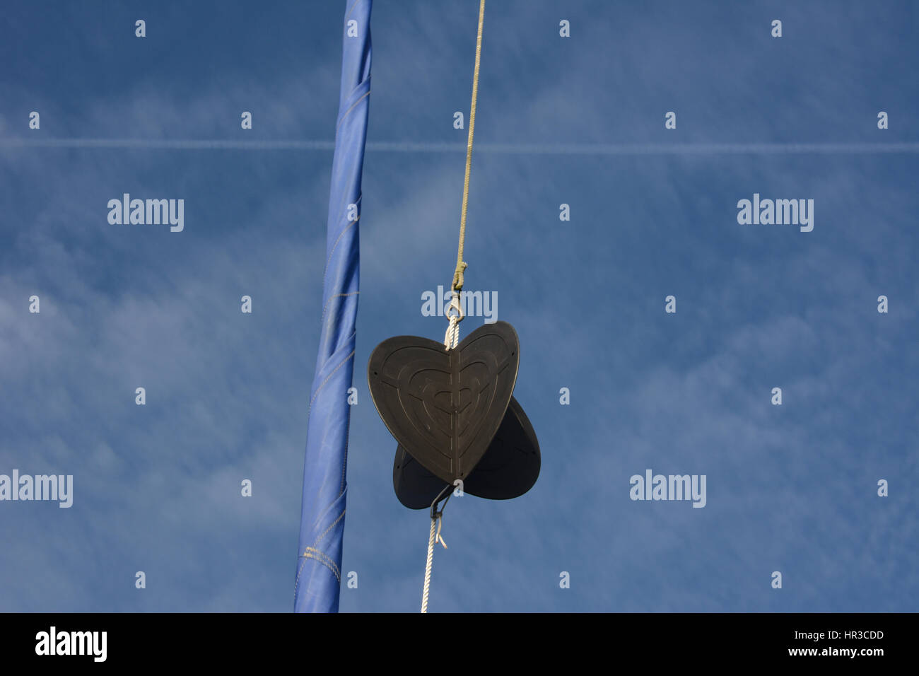Anchor ball in yachts rigging with rolled foresail against a blue sky ...
