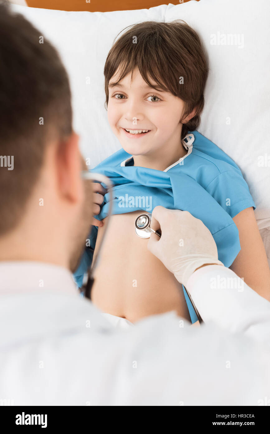 back view of doctor examining smiling little boy with stethoscope Stock ...