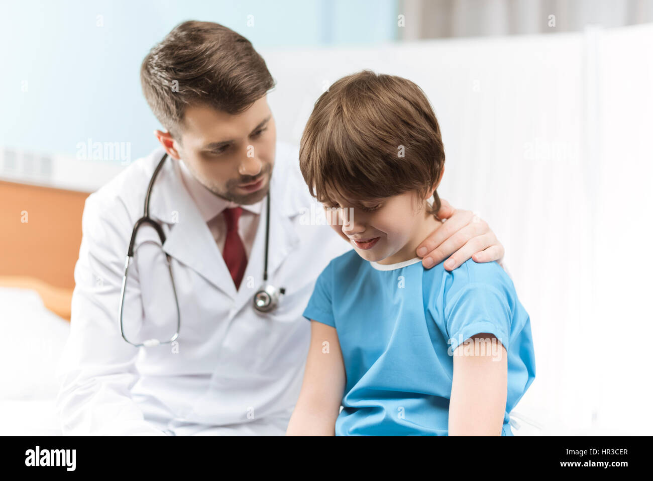 portrait of doctor cheering up little crying boy in hospital Stock ...