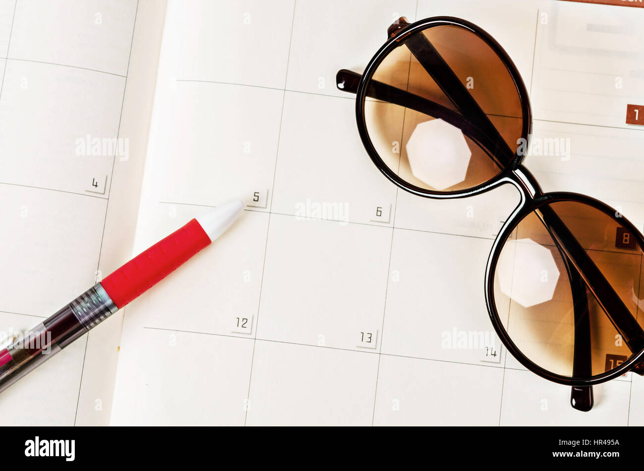 Sunglasses on open calendar page with pen Stock Photo - Alamy