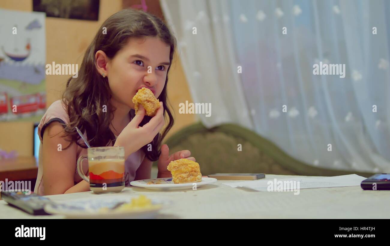 teen girl drinking the tea and eating cake, indoor lifestyle watching ...