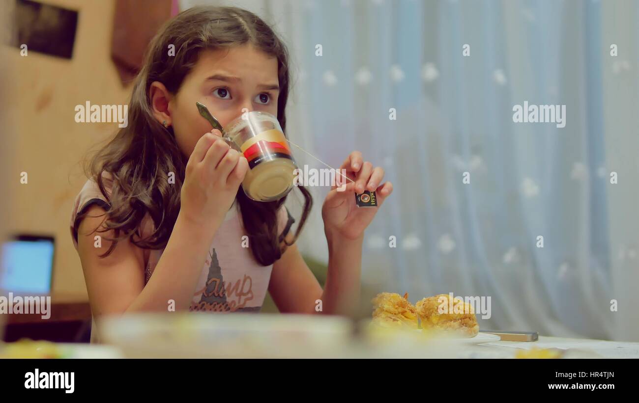 teen girl drinking the tea and eating cake, indoor lifestyle watching ...