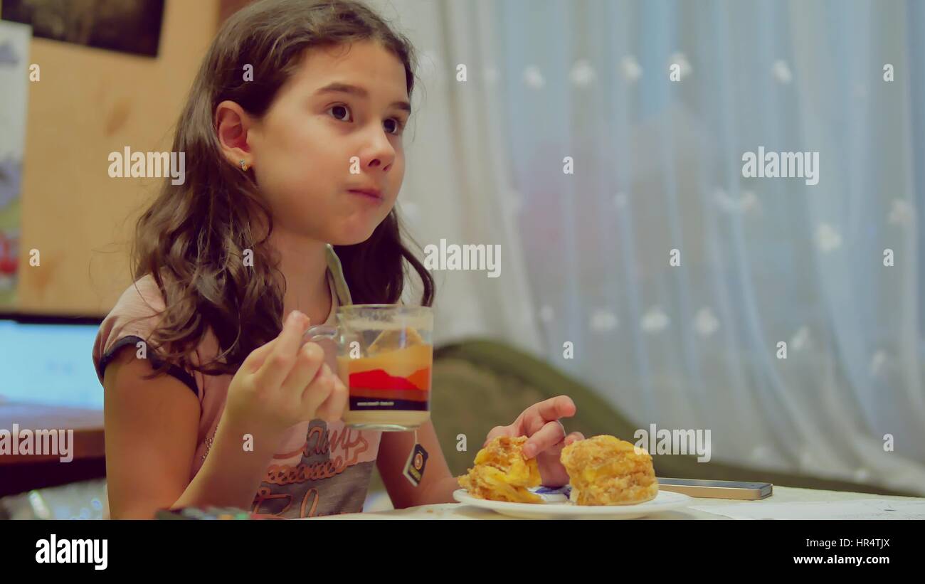 teen girl drinking the tea and eating cake, indoor lifestyle tv ...