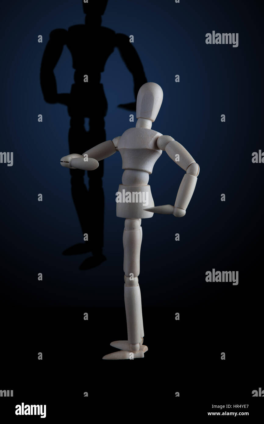 Wooden figurine flexing muscles in bodybuilder pose with shadow on dark ...