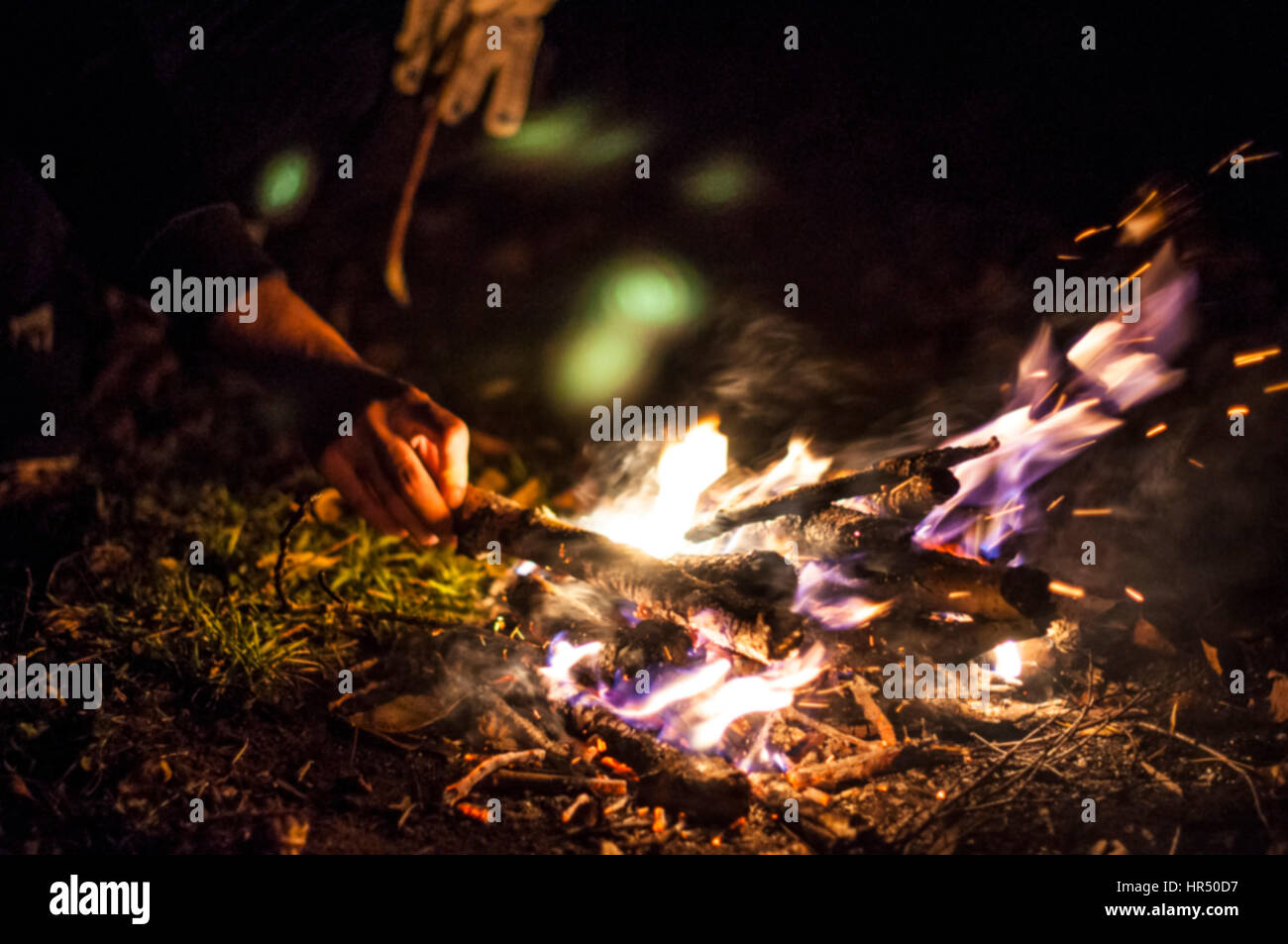 hand man traveler put wood on the fire in the open air at night in the ...