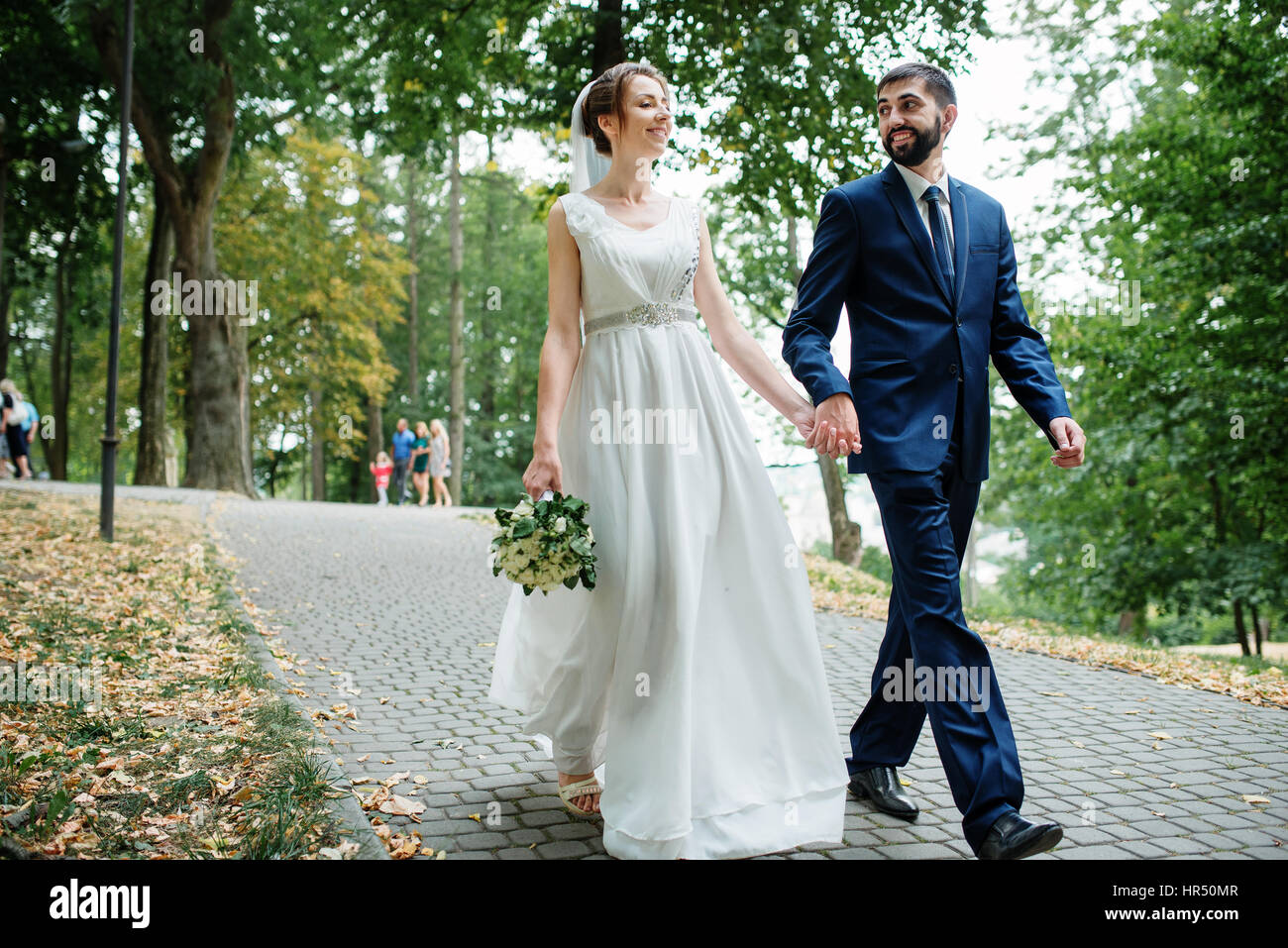 Wedding couple walking on path at green park Stock Photo - Alamy