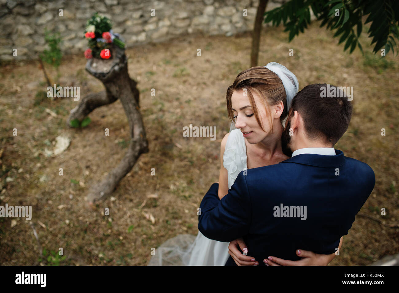 Groom kissing bride on neck background wooden stump with wedding ...