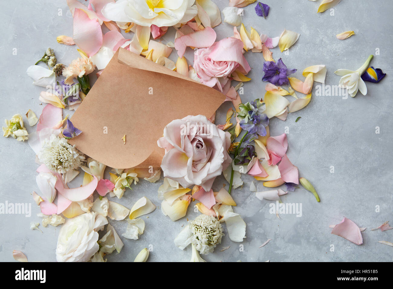 white envelope full of various flowers on a stone background . Flat lay ...