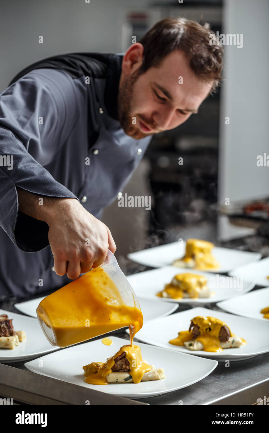 Chef pouring condimented vegetable sauce on tasty meat in restaurant ...