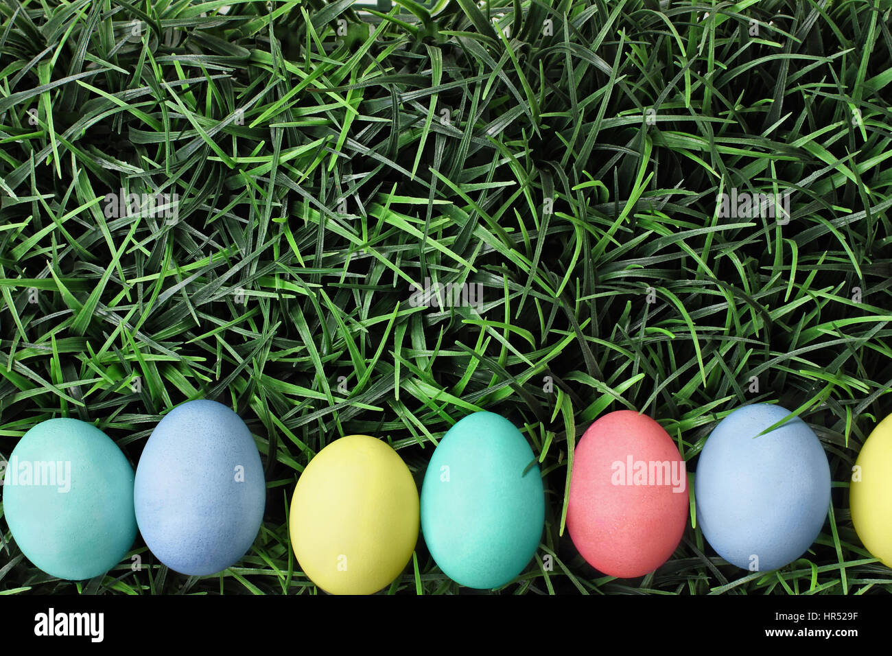 Overhead view of colorful Easter eggs lined up in a row over a ...