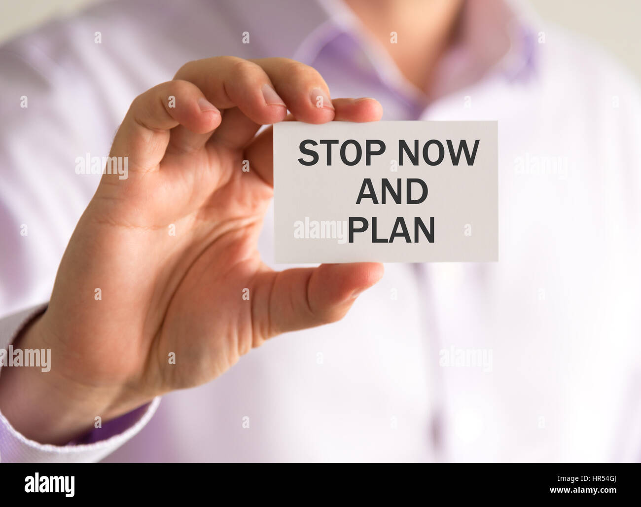 Closeup on businessman holding a card with STOP NOW AND PLAN message ...