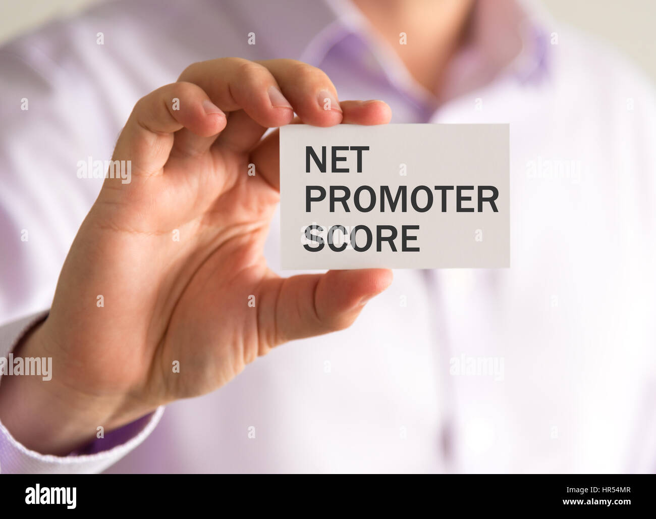 Closeup on businessman holding a card with NPS NET PROMOTER SCORE ...