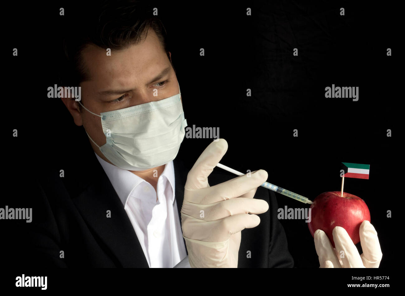 Young businessman injecting chemicals into an apple with Kuwaiti flag ...