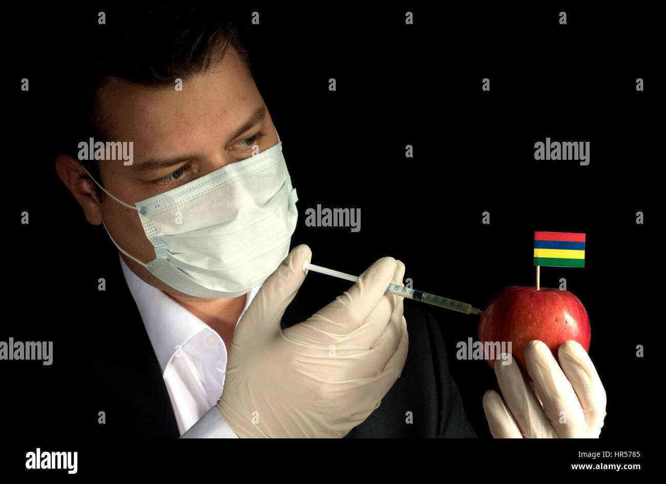 Young businessman injecting chemicals into an apple with Mauritius flag ...