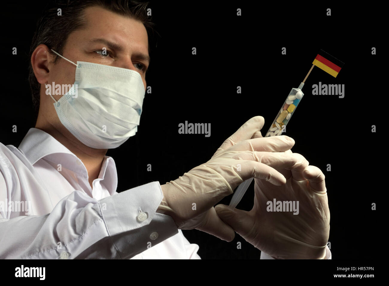 Young man as a doctor gives a medical injection to German flag on a ...