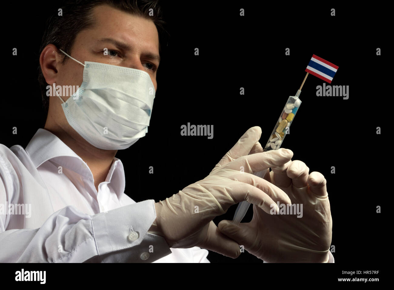 Young man as a doctor gives a medical injection to Thai flag on a black ...