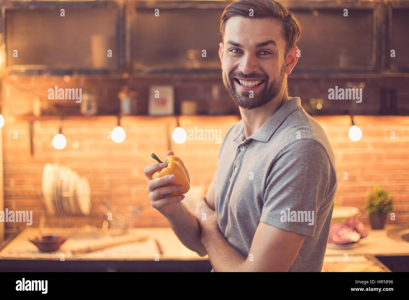 Young handsome man in kitchen. Man looking at camera and smiling while ...
