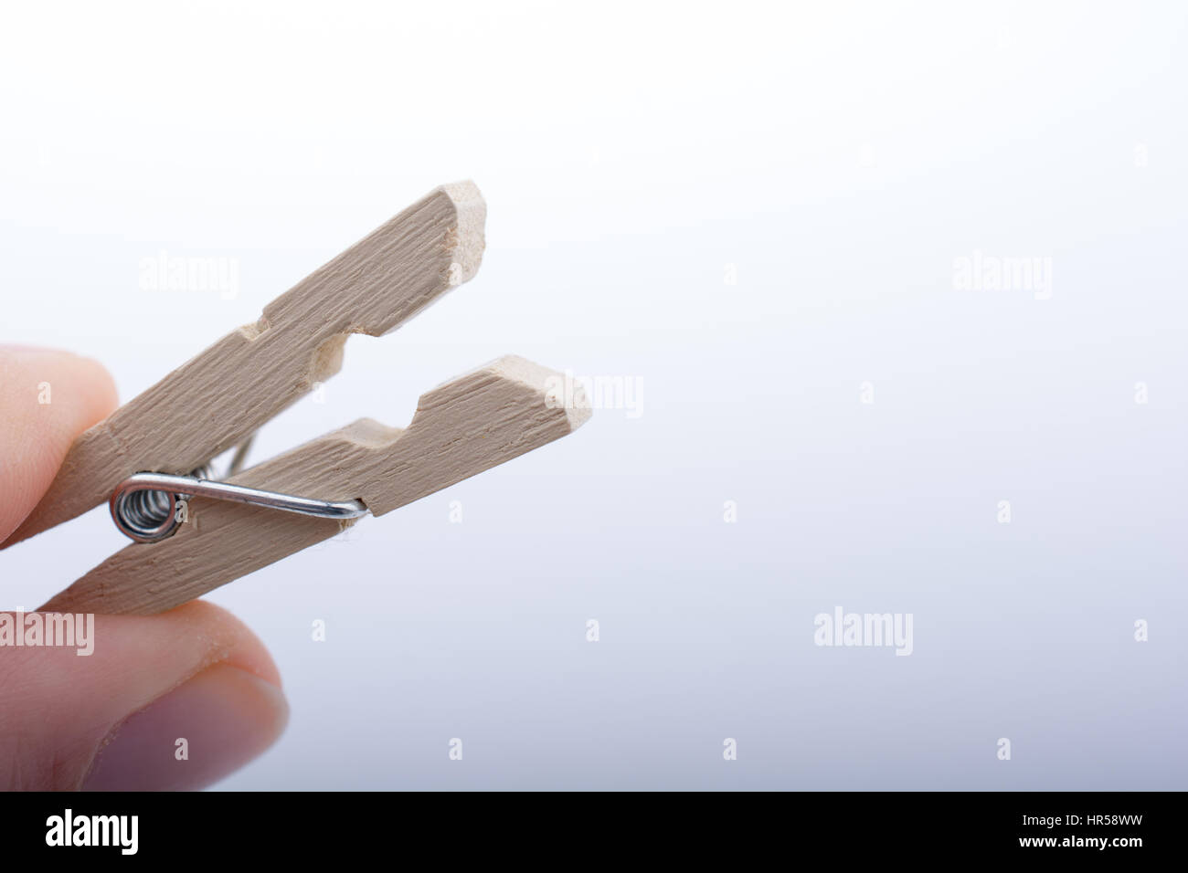 Hand holding a small wooden clothespin in hand Stock Photo - Alamy