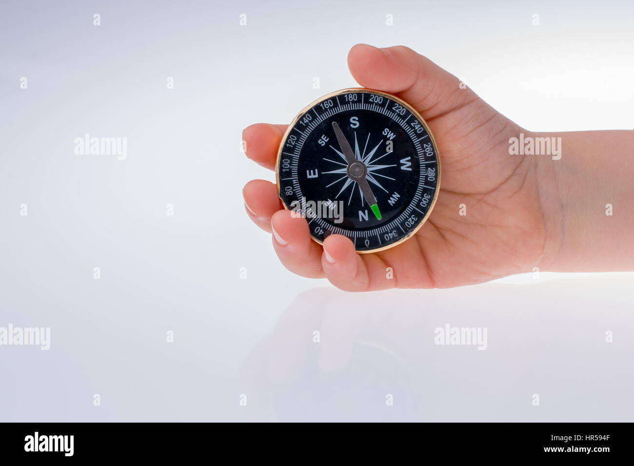 Child hand holding a compass on a white background Stock Photo - Alamy