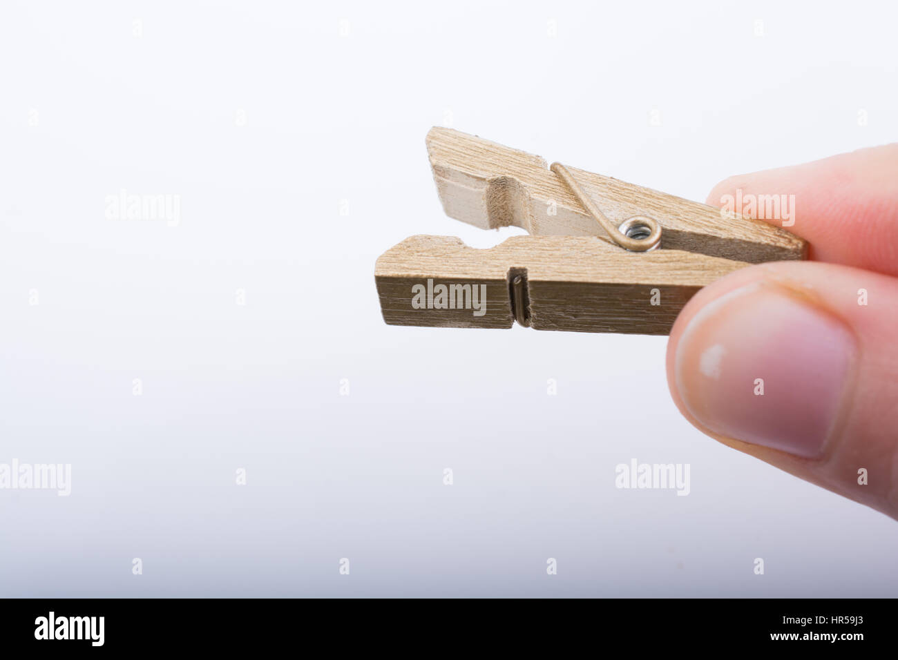 Hand holding a small wooden clothespin in hand Stock Photo - Alamy