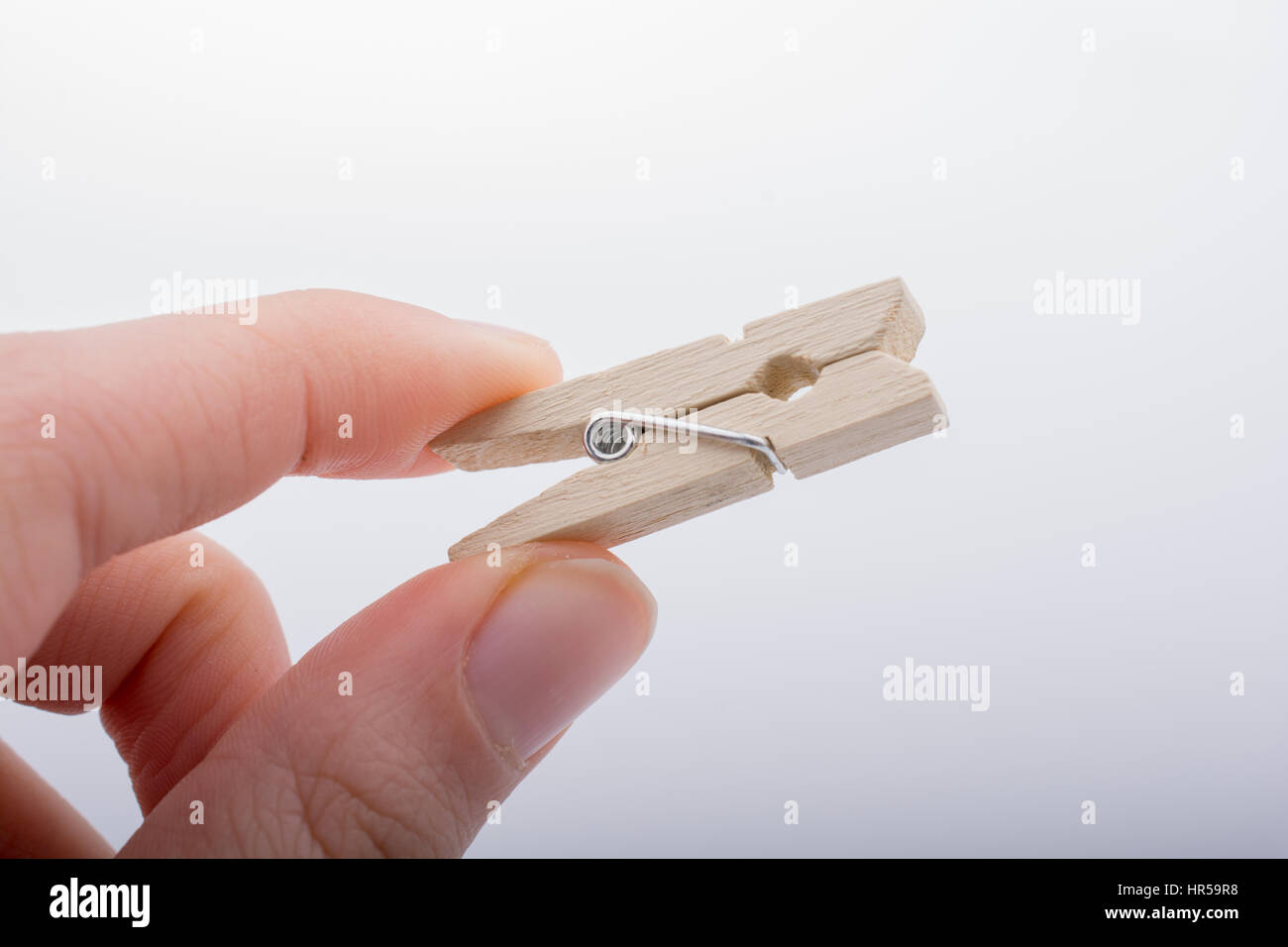 Hand holding a small wooden clothespin in hand Stock Photo - Alamy