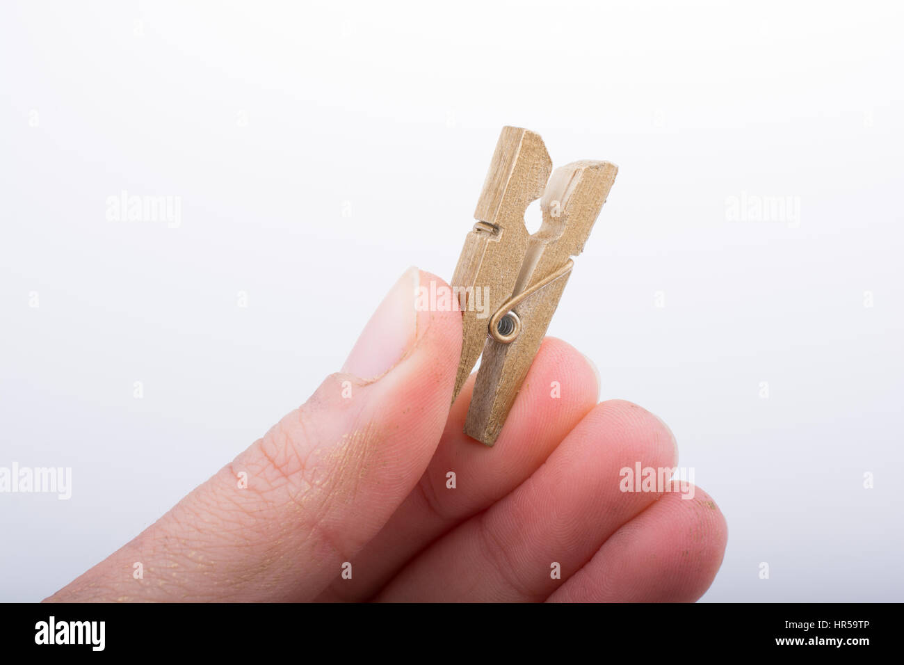 Hand holding a small wooden clothespin in hand Stock Photo - Alamy