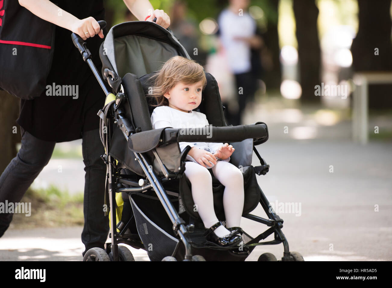 little and very beautiful baby girl sitting in the pram and waiting for ...