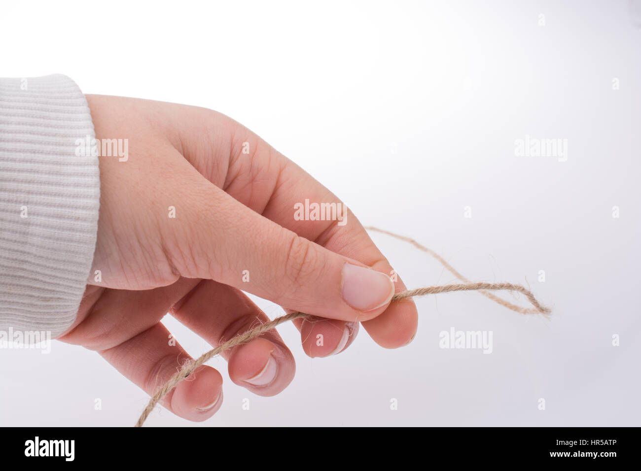 Hand holding linen thread on a white background Stock Photo - Alamy