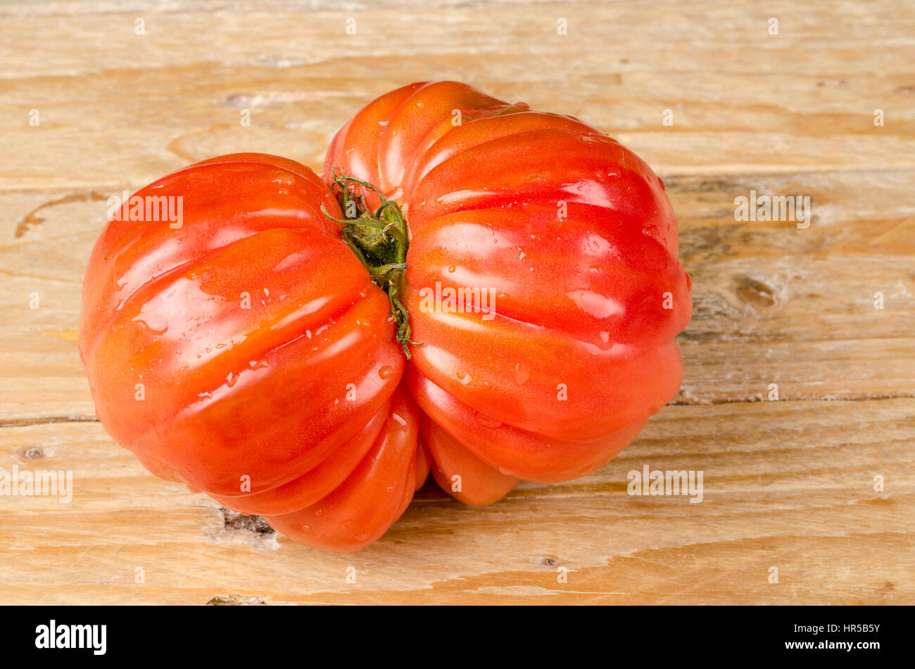 Wrinkled tomato of the particularly tasty Raf type on a rustic wooden ...