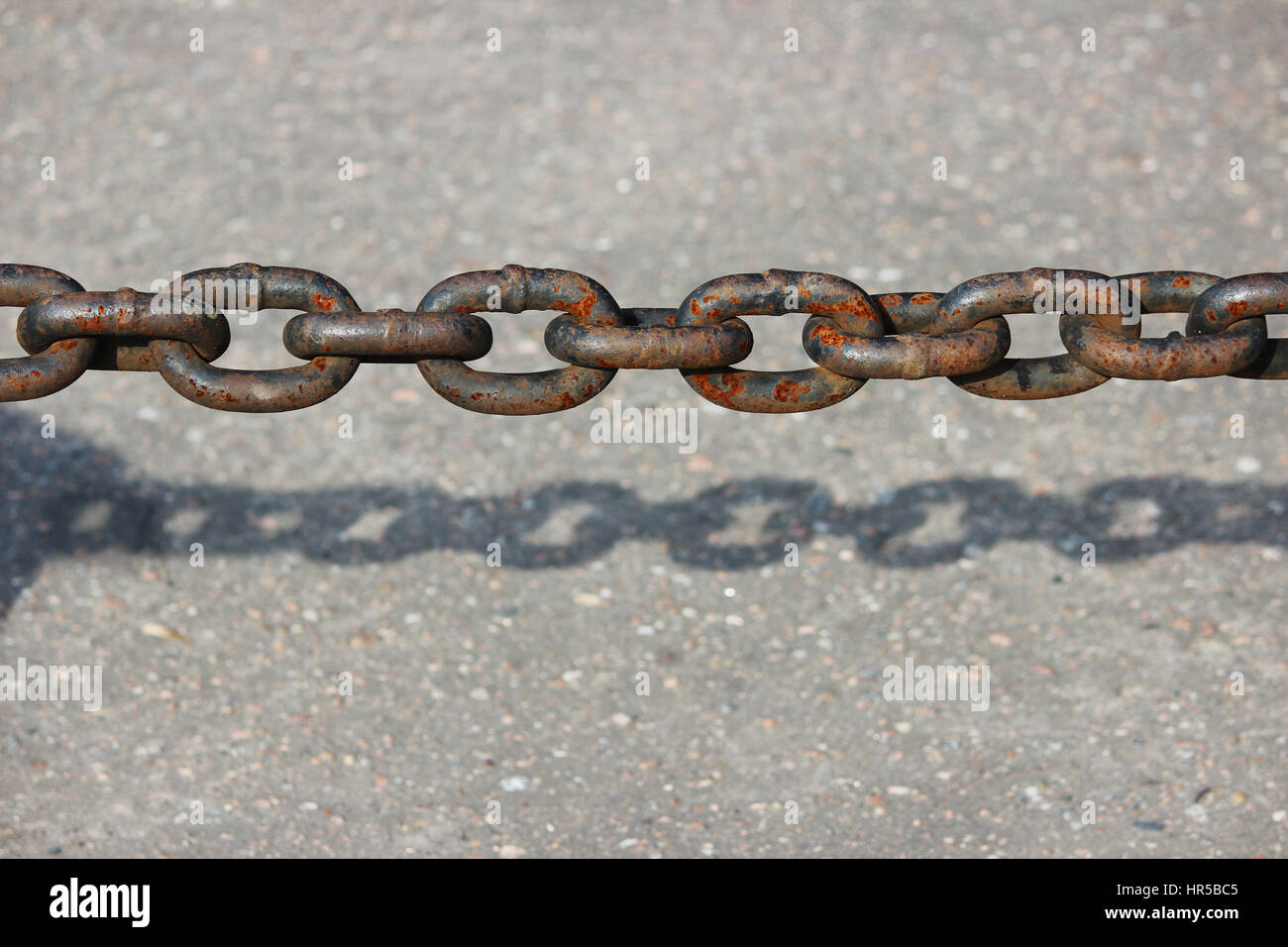 rusty metal chain hanging over the asphalt and casts a shadow Stock ...