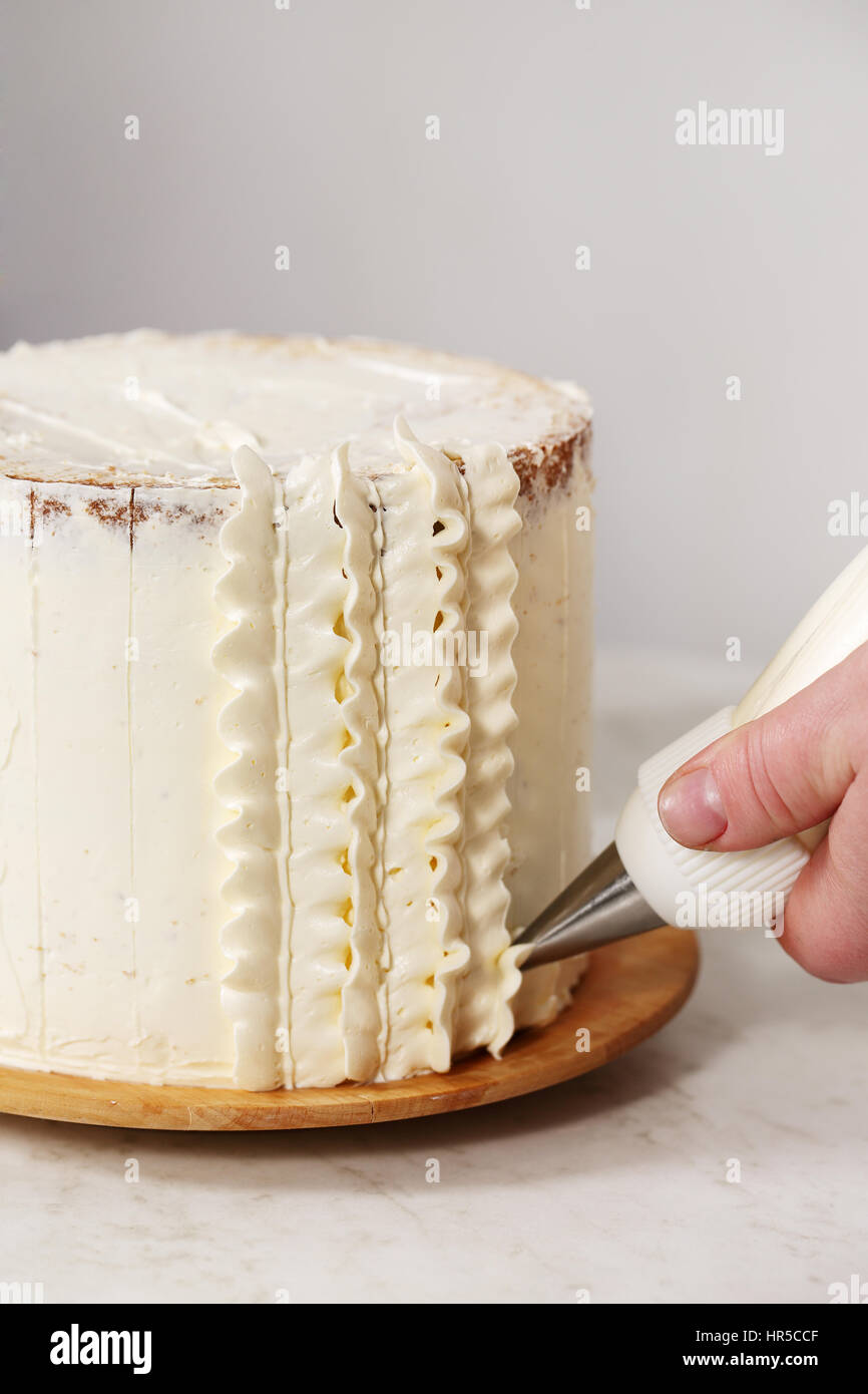 Woman decorate a cake with cream patterns Stock Photo - Alamy