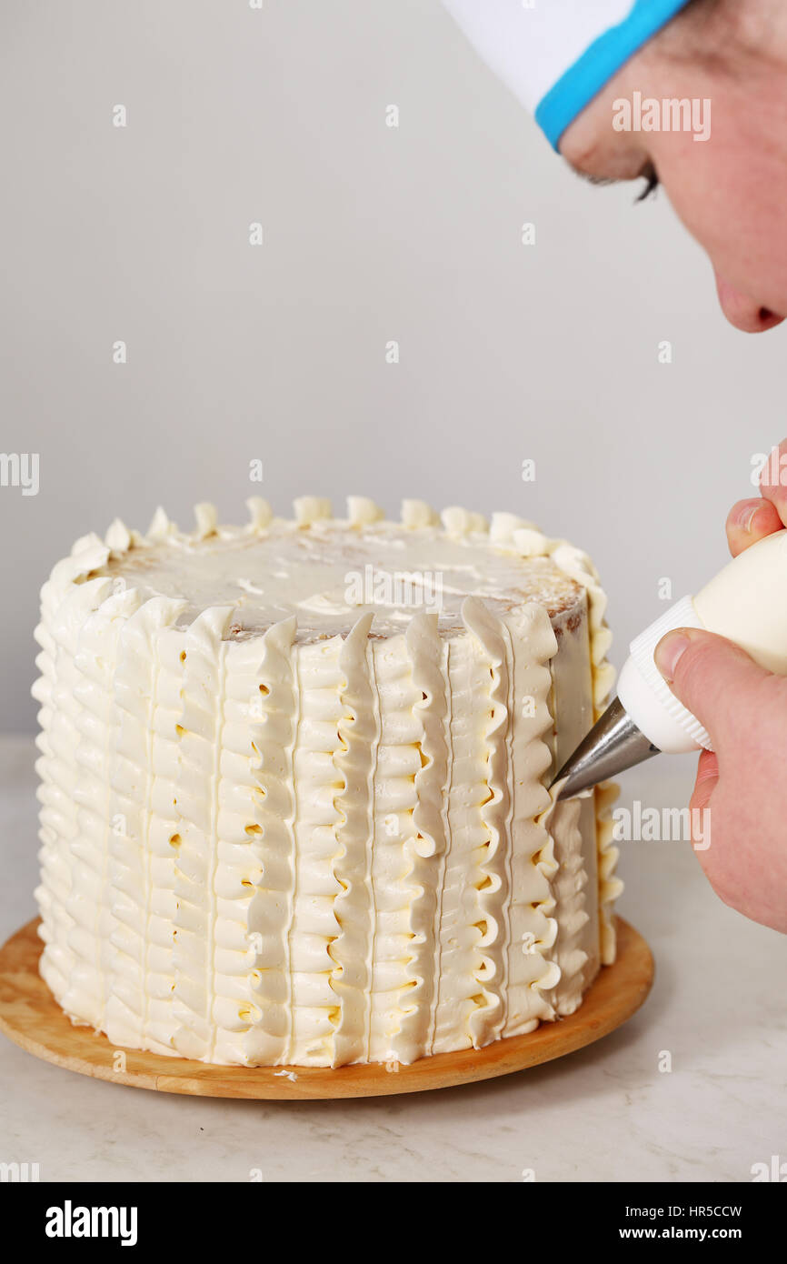 Woman decorate a cake with cream patterns Stock Photo - Alamy