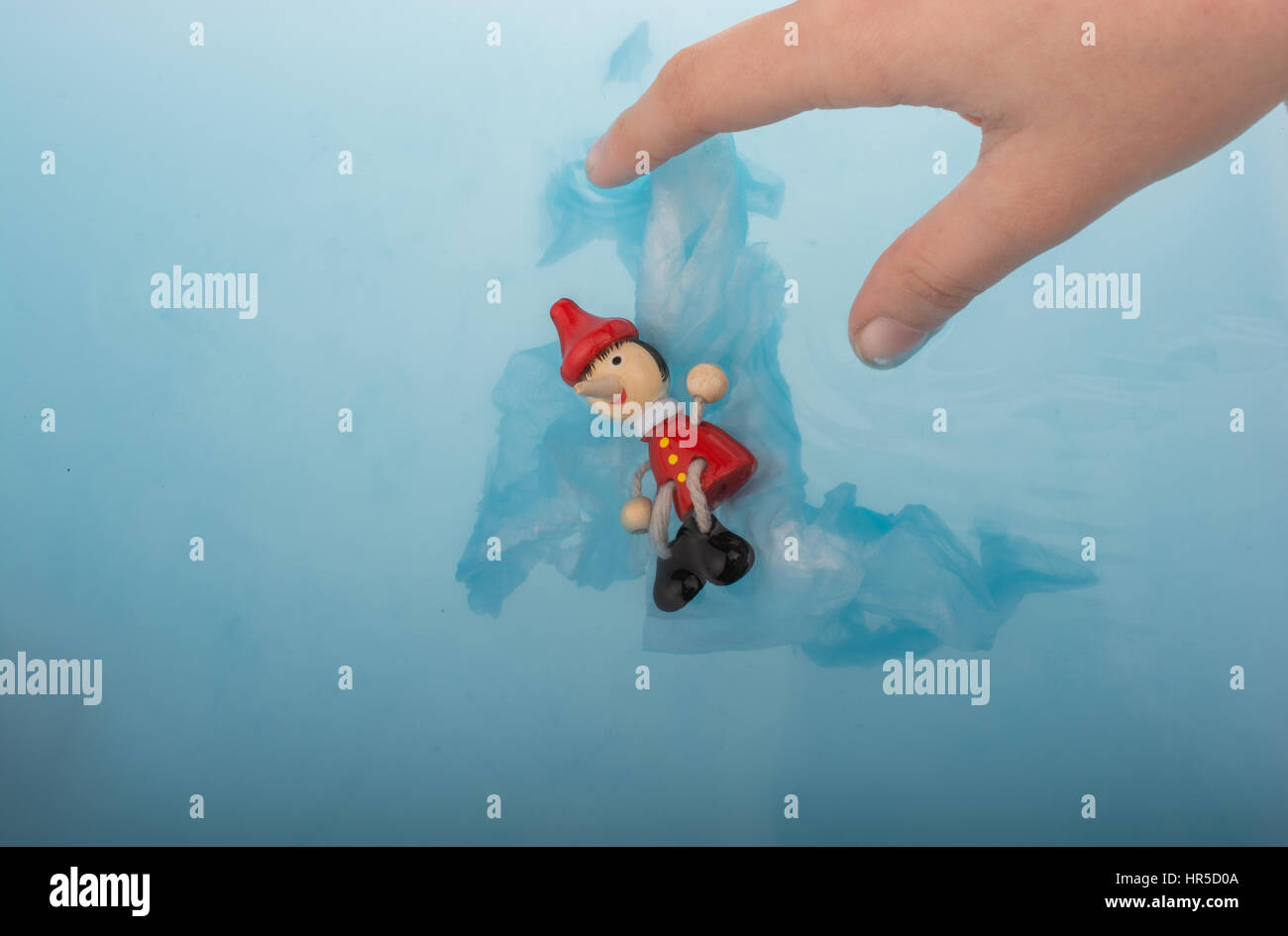 Hand holding wodden puppet Pinocchio on in blue water Stock Photo - Alamy