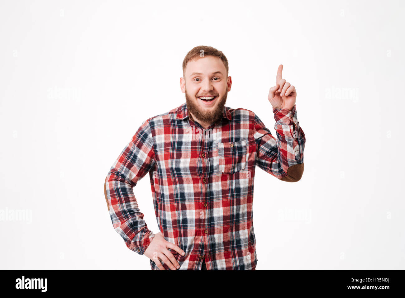 Happy Bearded man in shirt pointing up with arm at hip and looking at ...