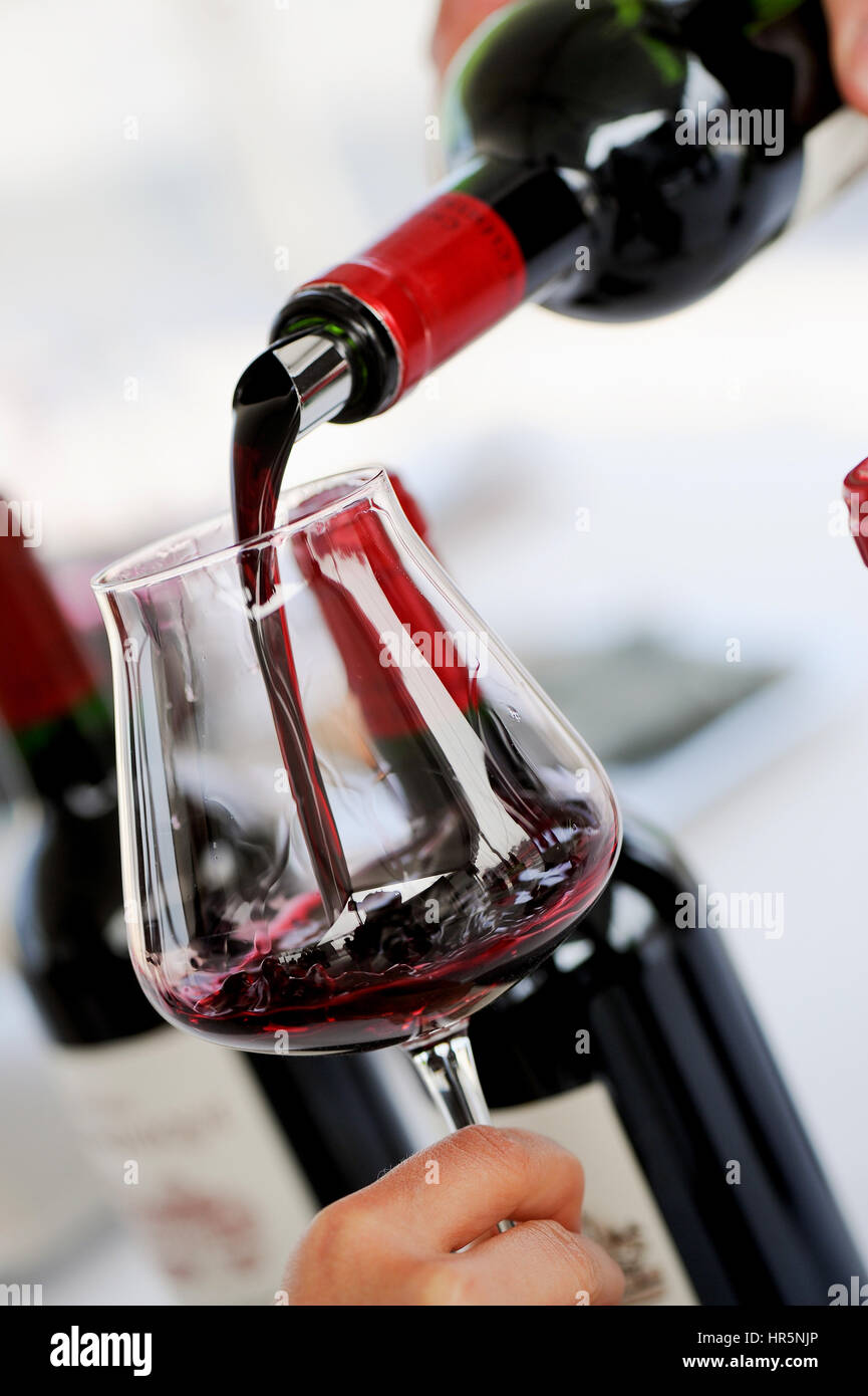 Tasting wine in a vinery-A man's hand is pouring red wine into a glass ...