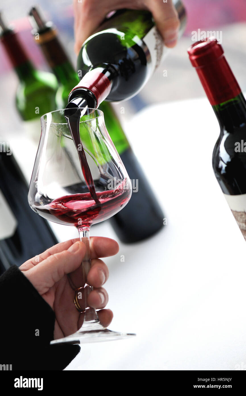 Tasting wine in a vinery-A man's hand is pouring red wine into a glass ...