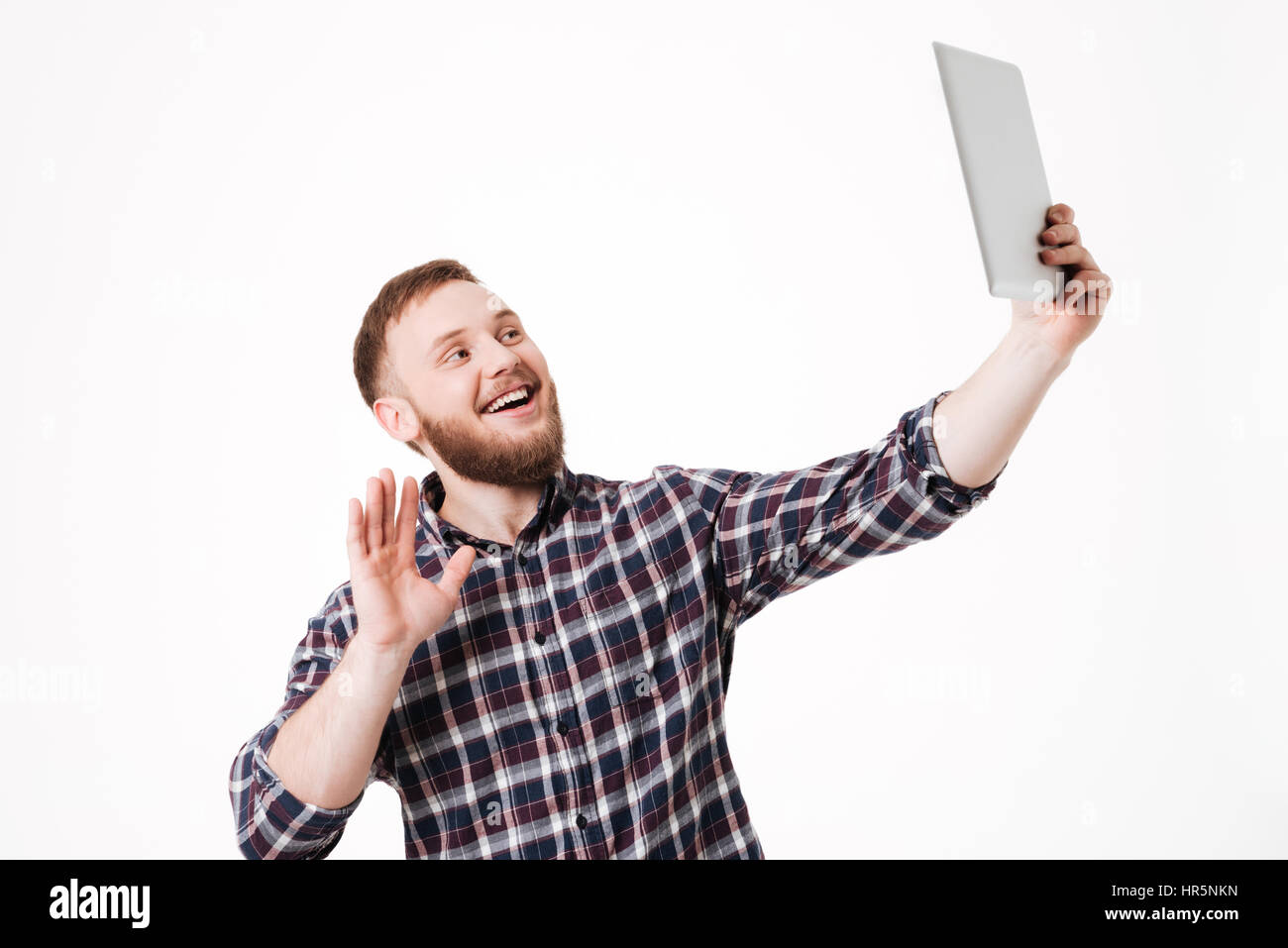 Man in shirt making selfie on tablet computer and waving at camera ...