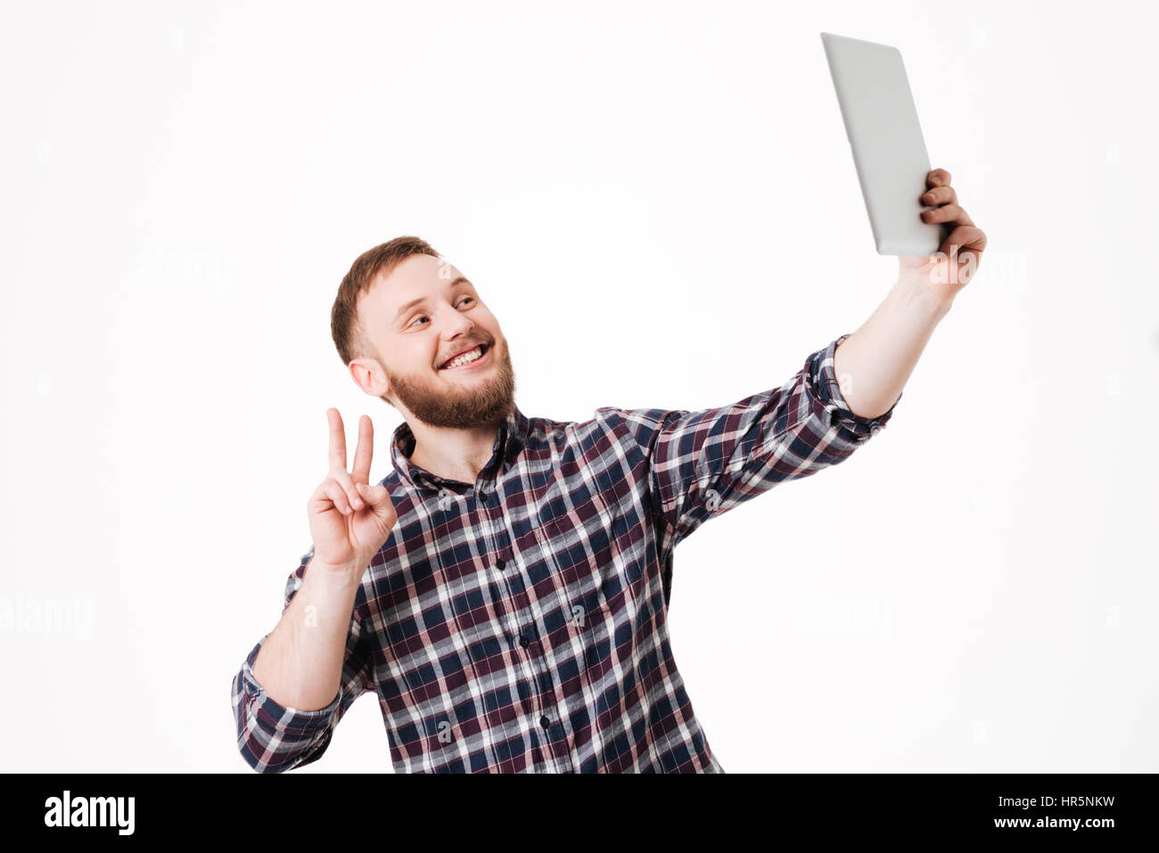 Man in shirt making selfie on tablet computer and showing peace sign ...