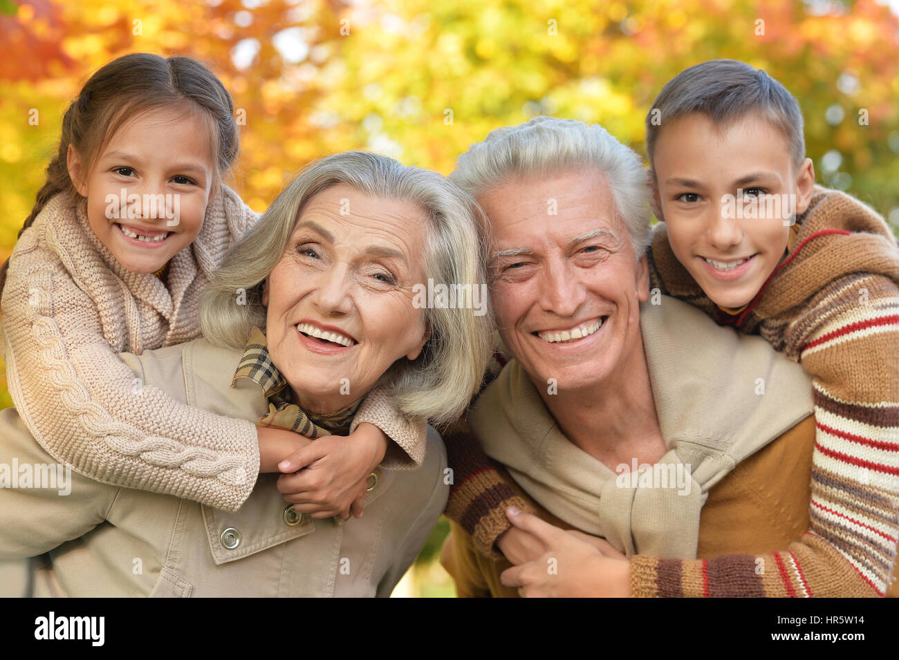 portrait of grandparents with grandchildren posing outdoors in autumn ...