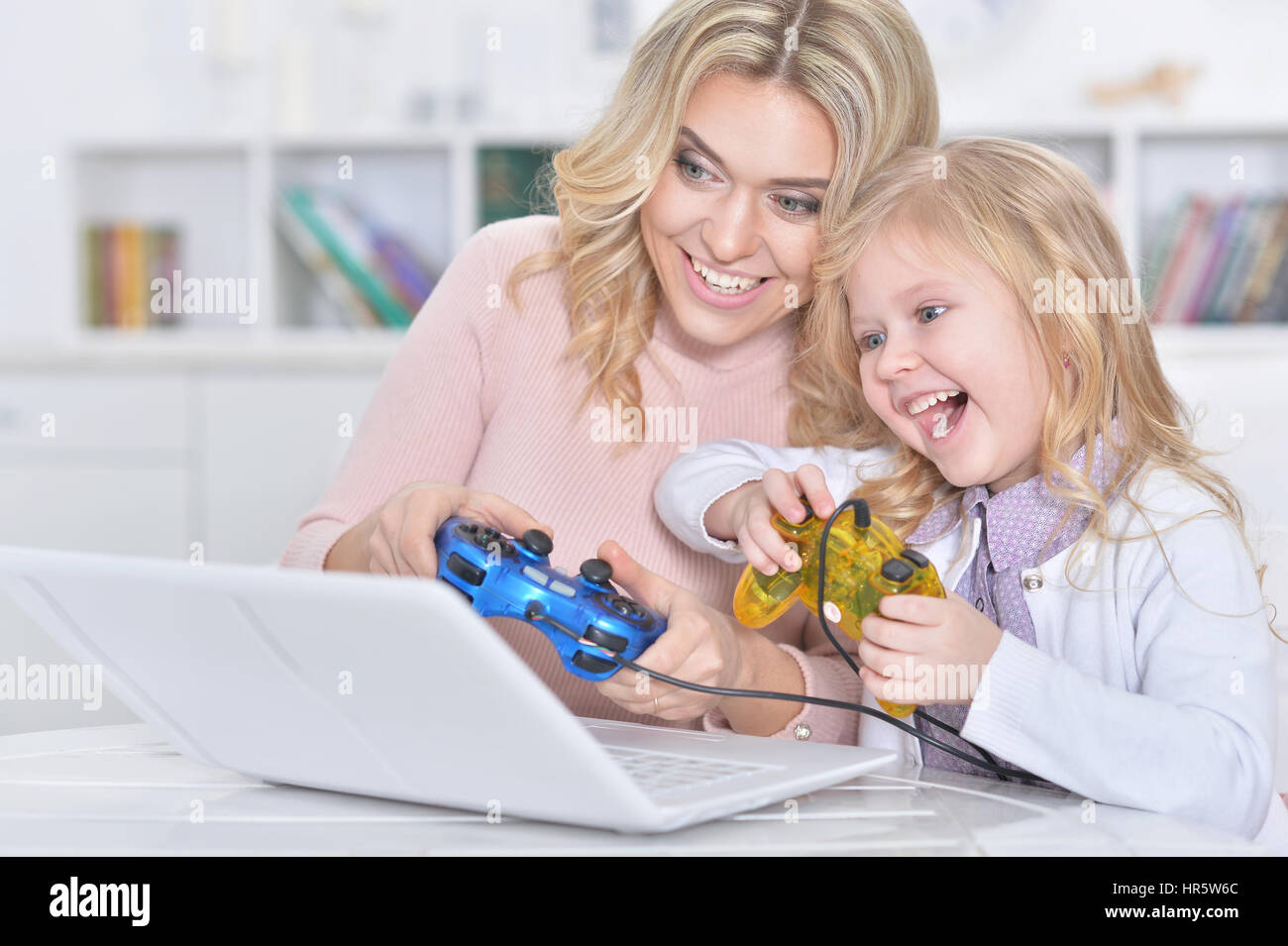 young woman and little girl playing video game on laptop Stock Photo ...