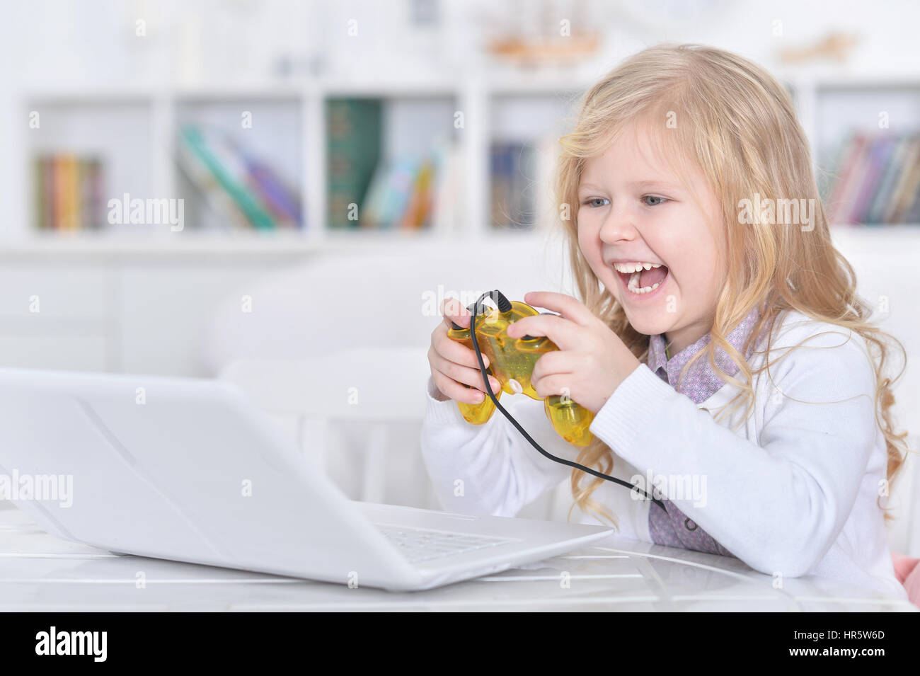 happy little girl playing video games on laptop Stock Photo - Alamy