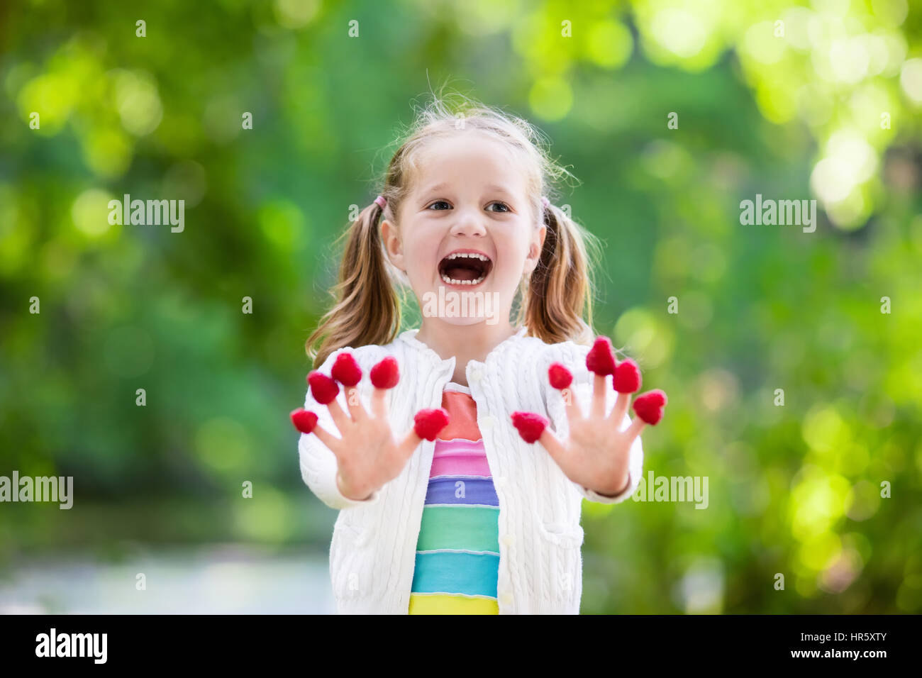 Child picking raspberry. Kids pick fresh fruit on organic raspberries ...