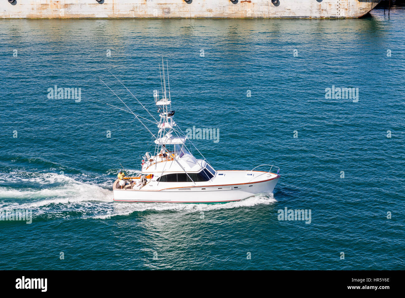White cabin cruiser speeding across blue water in harbor Stock Photo ...