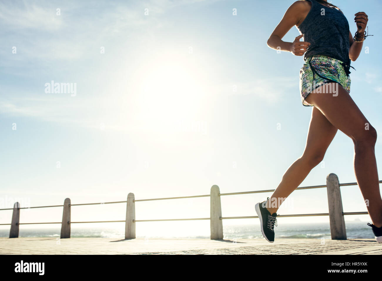 Cropped shot of fitness woman running on ocean front. Healthy female ...