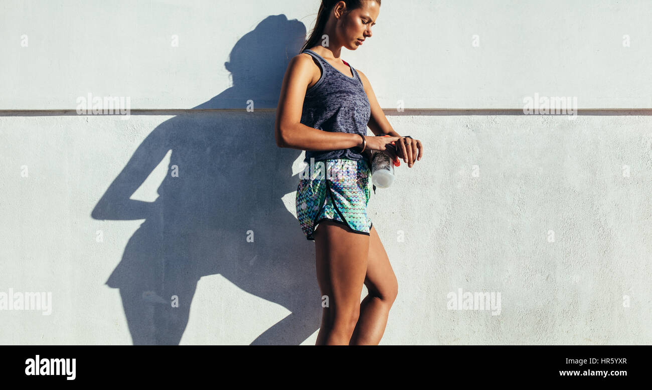 Young woman checking fitness progress on her smart watch. Female runner ...