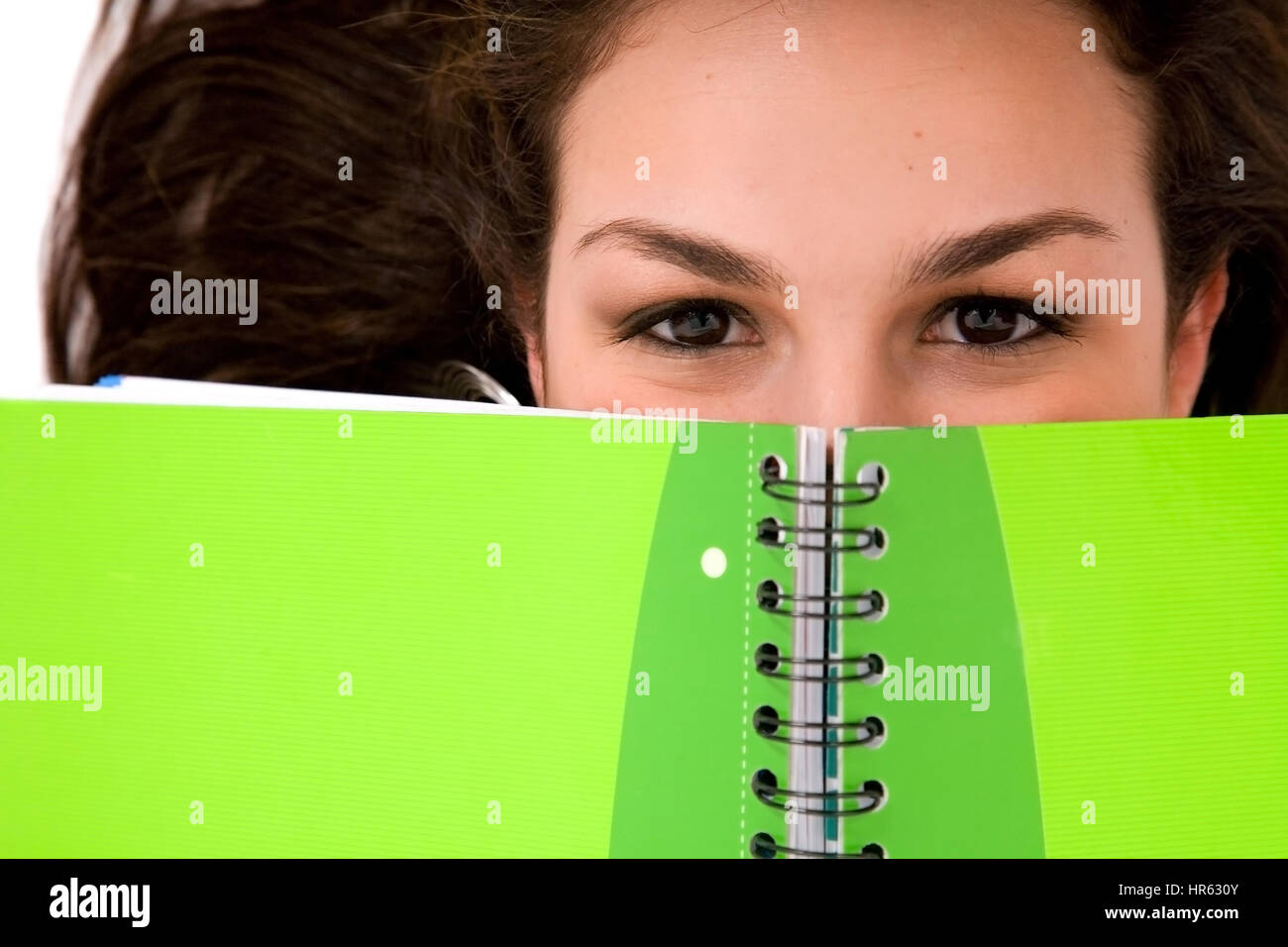 beautiful female student peeping over a green notebook while lying on ...