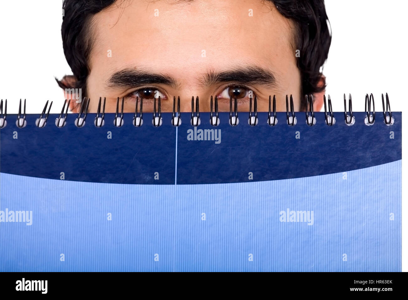 student peeping over a blue notebook isolated over a white background ...