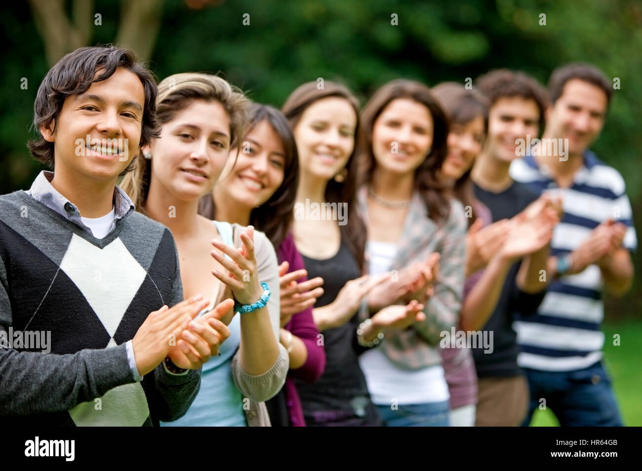 casual friends smiling and clapping upwards in the park Stock Photo - Alamy