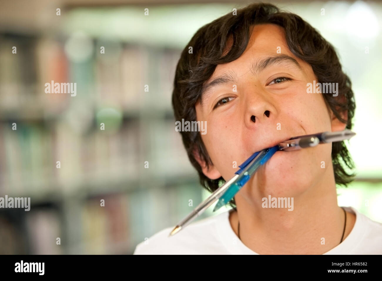 Student in a library with his mouth full of pens and pencils Stock ...
